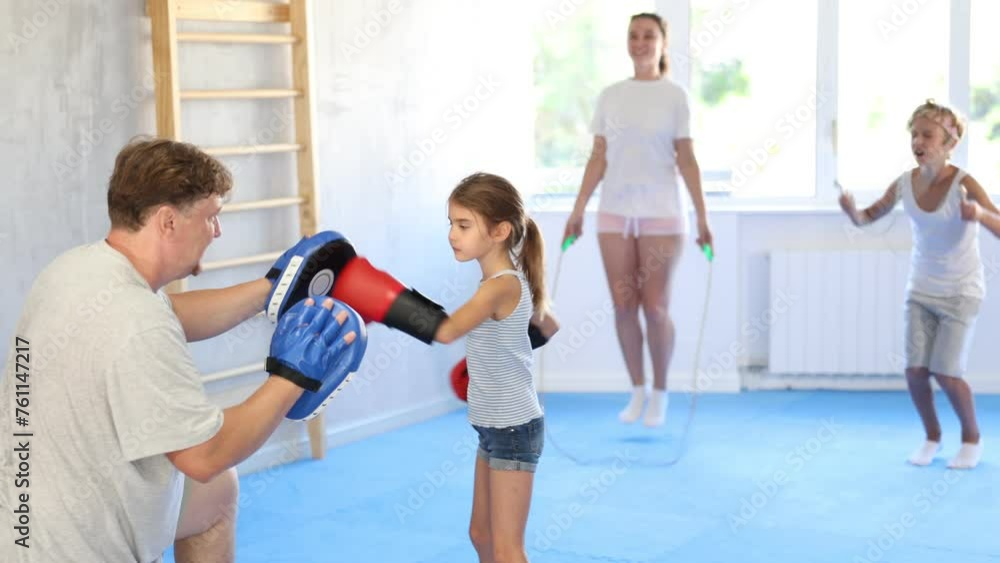 Father and daughter wearing boxing gloves train boxing punches in ...
