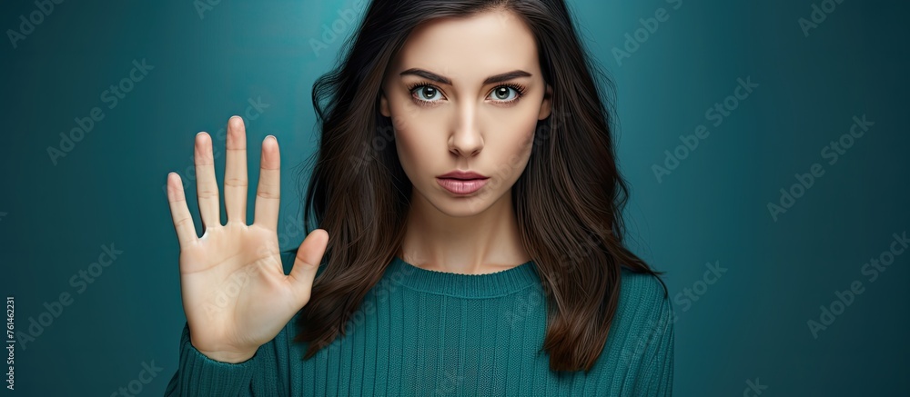 The woman is creating a stop sign with her hand, using her fingers and ...