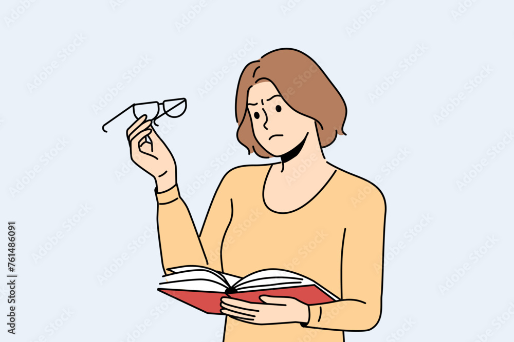 Woman experiences vision problems, reading book and looks at glasses ...