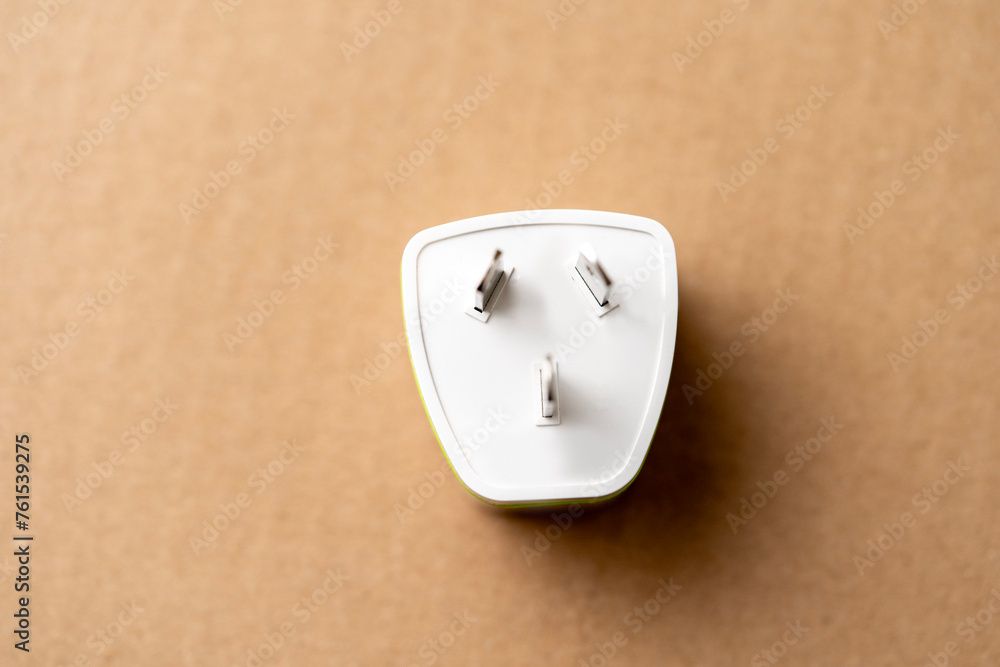 A white fork with a green stripe on it. The plug is on a brown surface ...