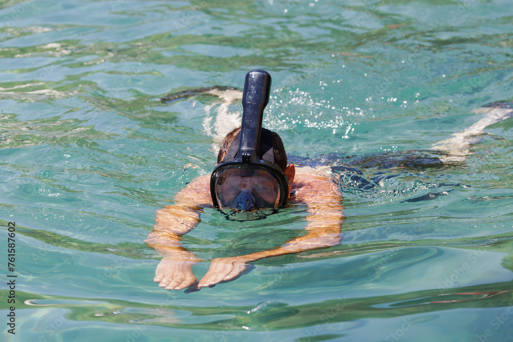 Foto de Caucasian man snorkeling in clear waters with black goggles and ...