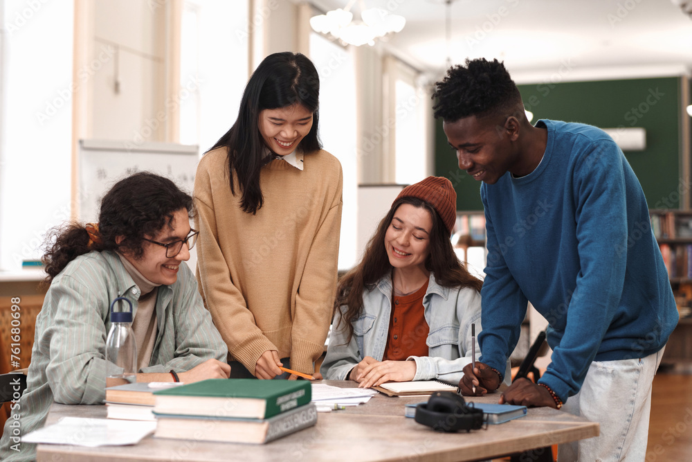 Multiethnic group of students studying together around table in ...
