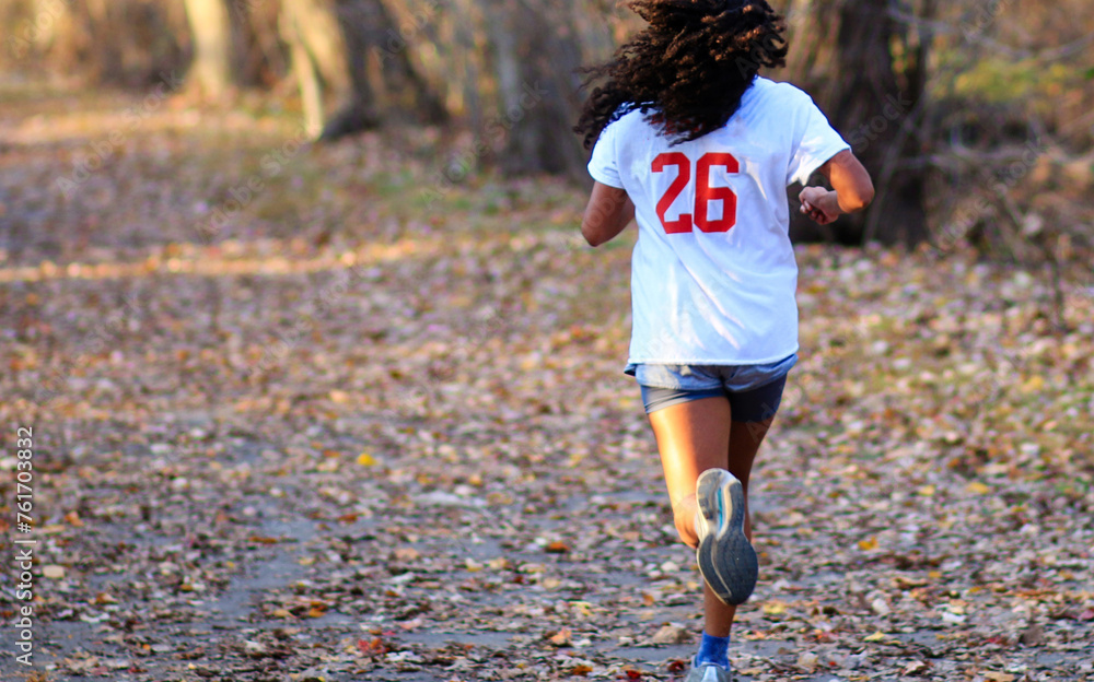 Teenage girl running on a path fuill of leaves training for distance ...