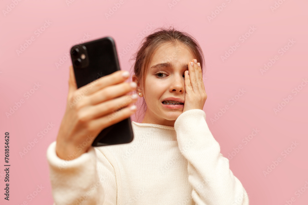 sad teenage girl with braces uses a smartphone and suffers from failure ...