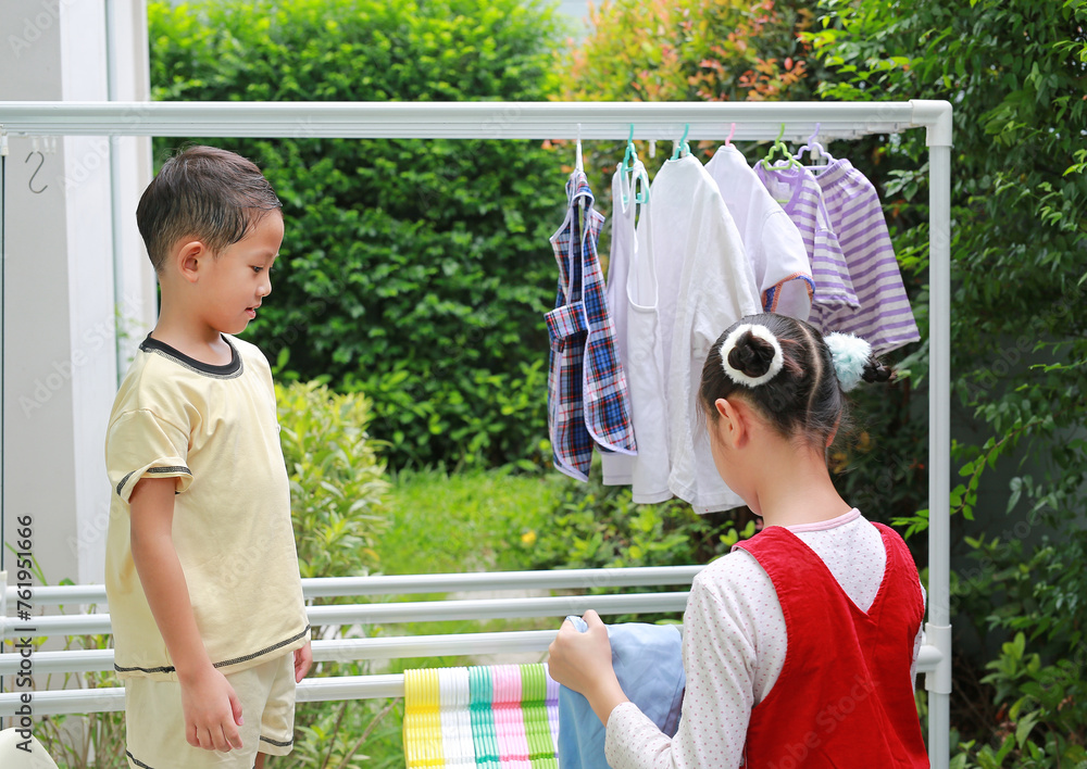 Portrait of Asian girl and boy helping to do dry the clothes at garden ...