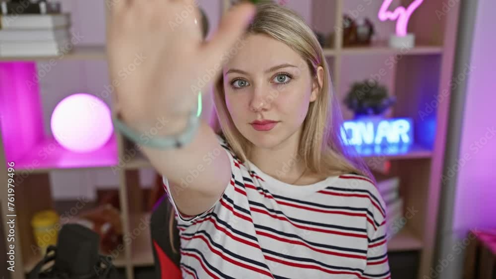 Serious blonde woman streamer in gaming room halts with firm stop sign ...