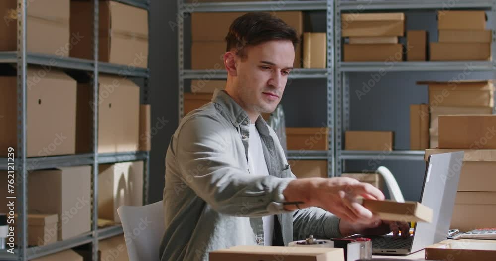 Warehouse male young worker laptop fixing incoming boxes, picking ...