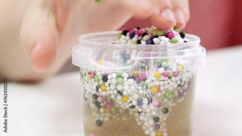 The child's hands are touched in close-up, and a transparent slime with ...