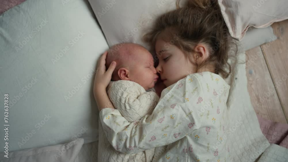 Portrait of big sister cuddling newborn, little baby. Girl lying with ...