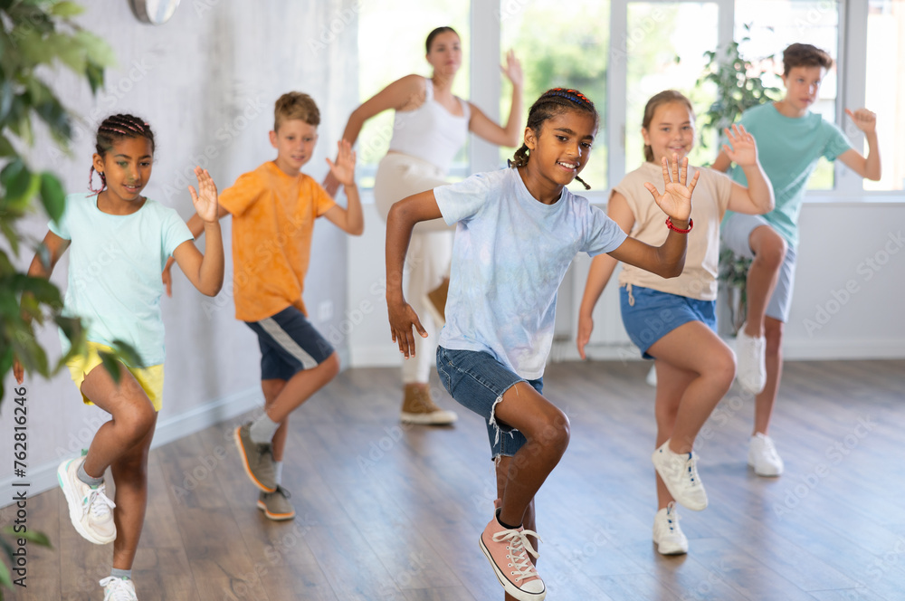Active preteen children practicing Hip-hop dance with young teacher in ...