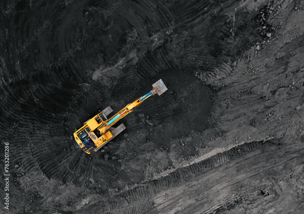 Coal mining in an open pit. Mining excavator loads coal in haul truck in quarry. Excavator ...