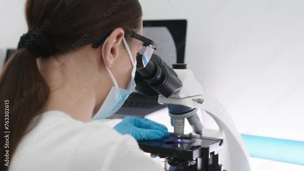 Scientist in a modern medical laboratory looking into a microscope ...