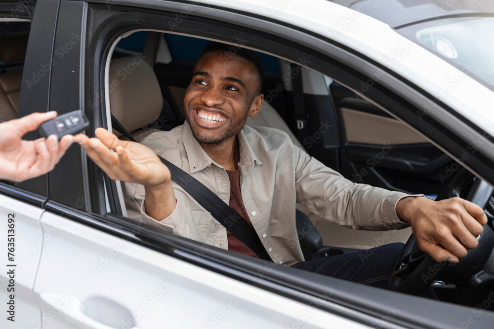 Test drive of a new car. Young black man grabs the car keys while ...