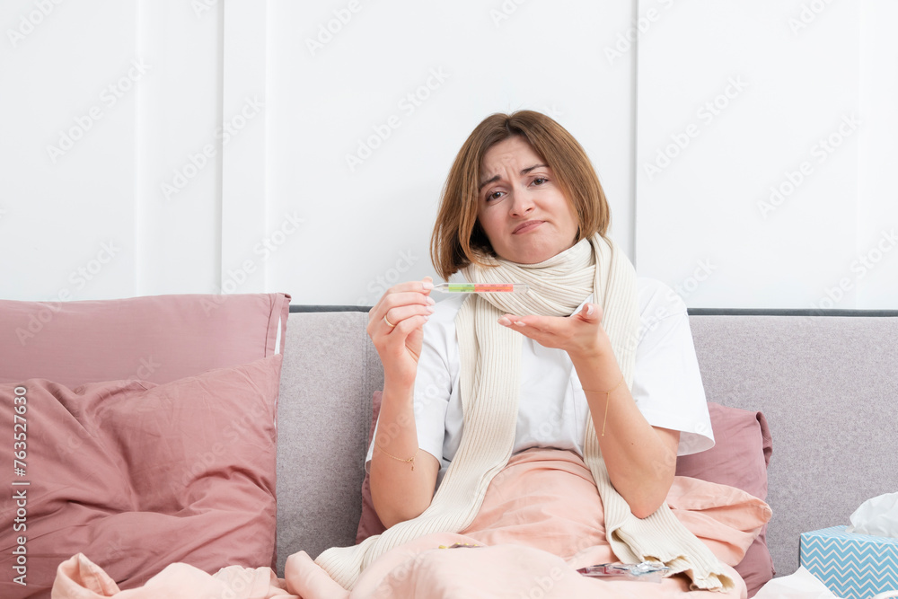 Young sick woman has a cold and high fever while checking body ...