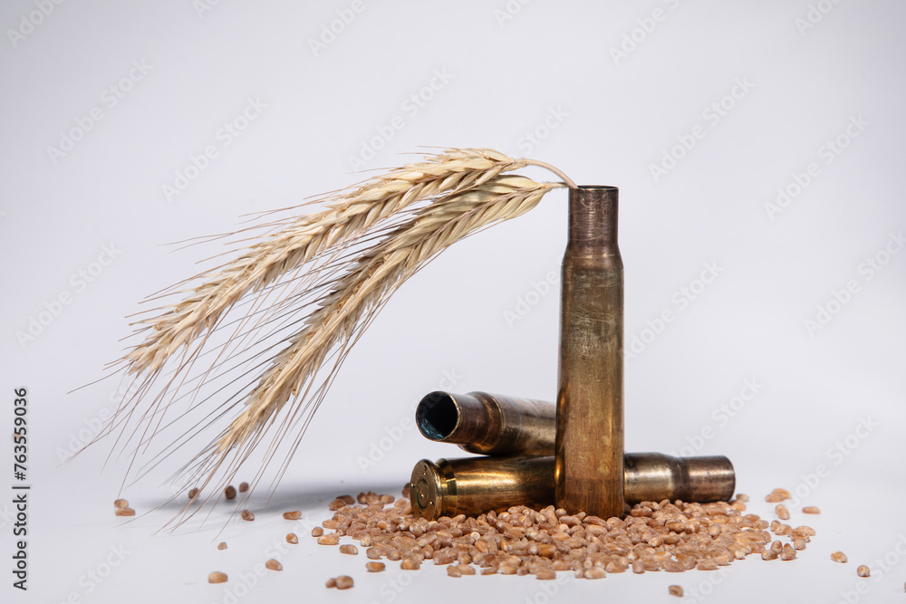 Three large bullet casings, sprigs of wheat on top of the grain ...