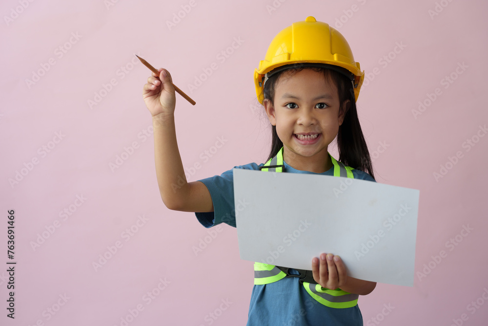 A cute girl wearing a yellow construction hat or safety helmet standing ...
