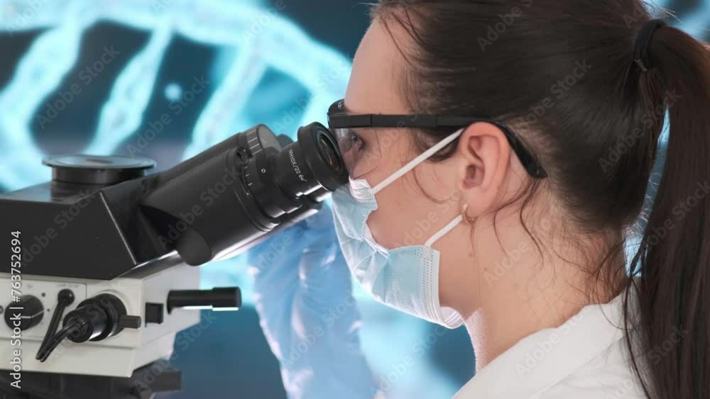 Close-up of a scientist examining samples under a microscope in a ...