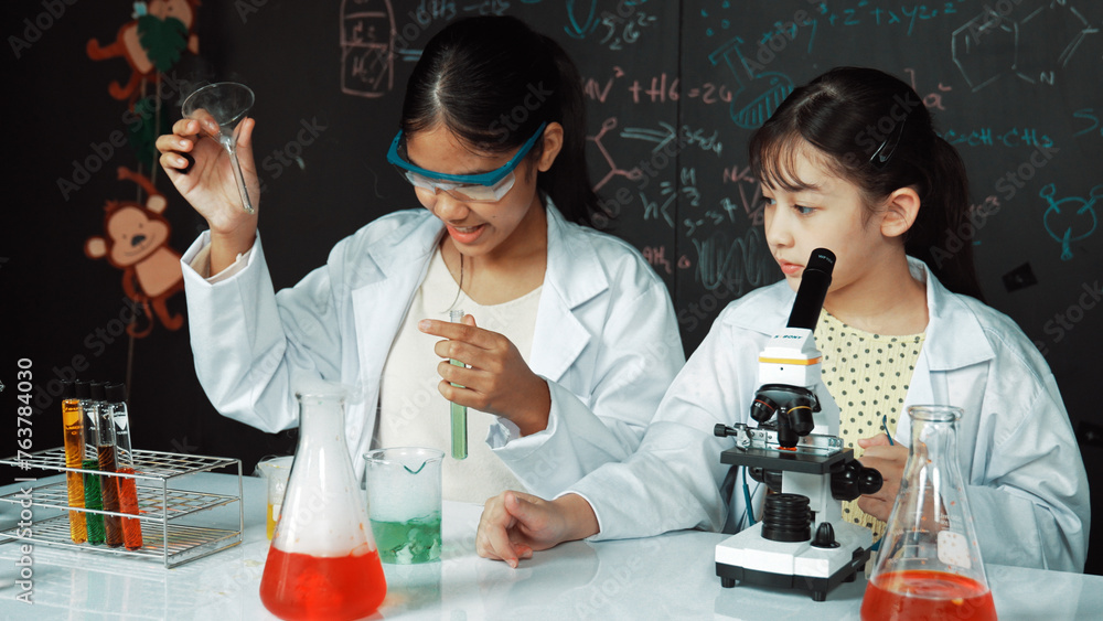 Young highschool student doing experiment by pouring sample in test ...