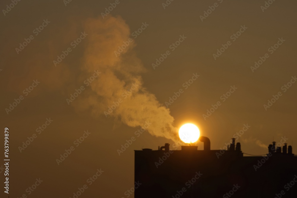 Smoke coming out of the chimney of a multi-family building against the ...