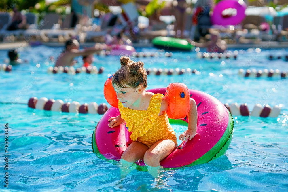 Happy little girl with inflatable toy ring float in swimming pool ...