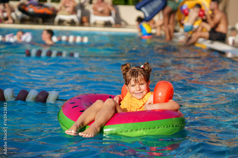 Happy little girl with inflatable toy ring float in swimming pool ...