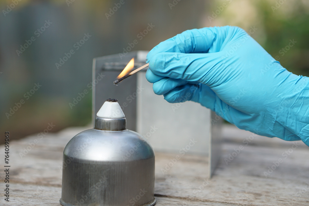Close up hand wears blue glove, hold a burning match to light fire on ...