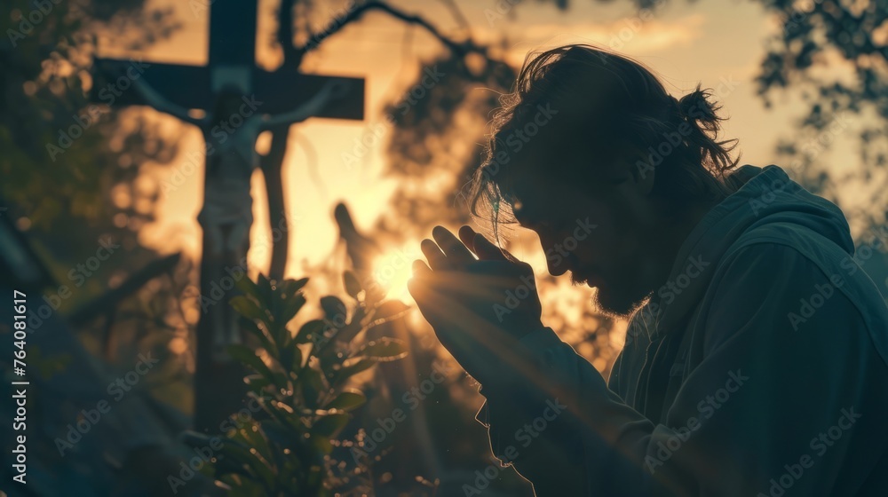 Man kneels next to cross while praying, man kneels in prayer in front ...