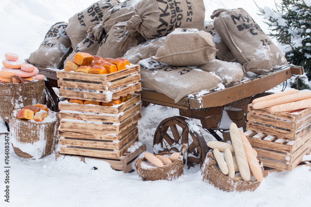 Loaves of bread in wooden pallets in the snow. Bags of flour on the ...