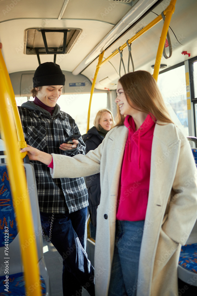 Young people standing in public transport, tram, bus. Easy of access to ...