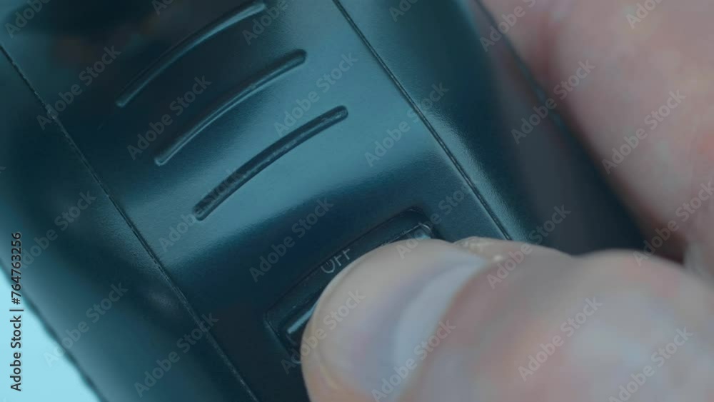 In a man's hand there is an electric shaver with rotating blades and a ...