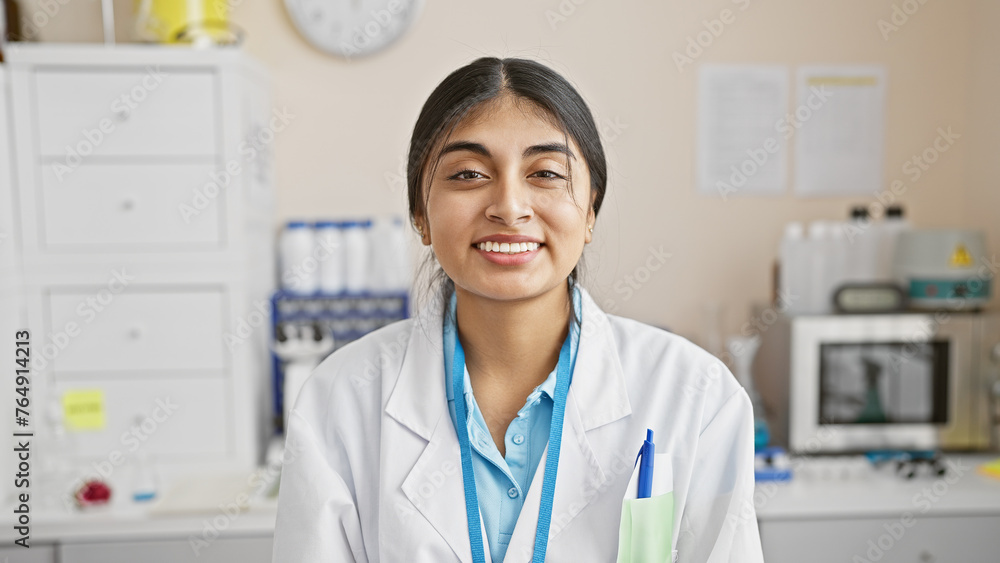 Young indian woman with long hair, smiling in a white lab coat in a ...