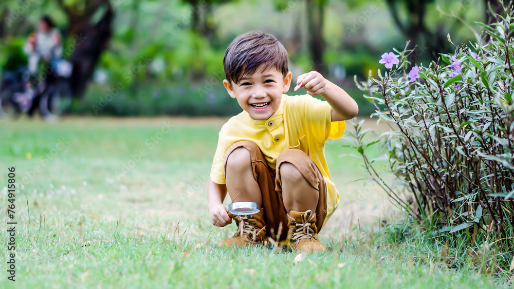 Mixed race little boy exploring the nature with magnifying glass ...