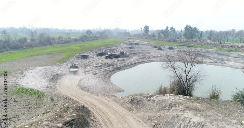 Ariel View of the tractor is filling soil in the trolley with tractor's ...