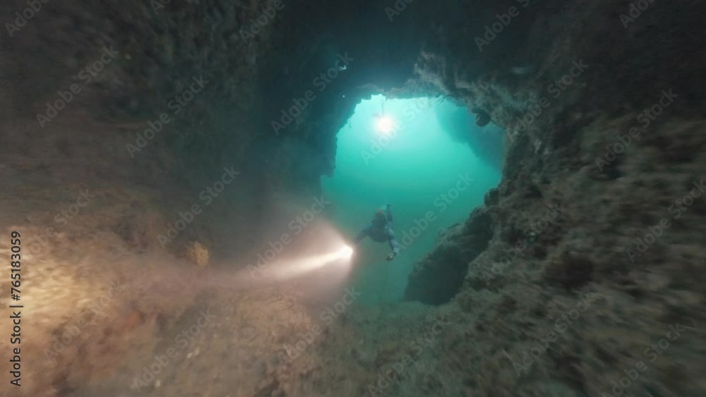 Cave freediving. Man freediver dives inside the cave with torch and ...