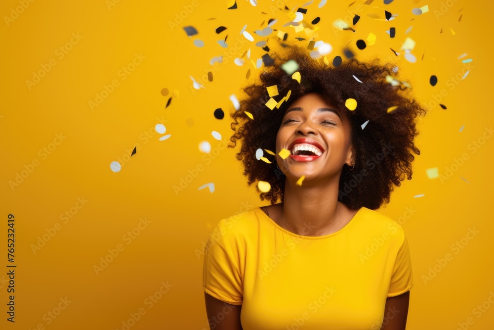 Radiant woman with a big smile enjoying a confetti shower on a vibrant ...