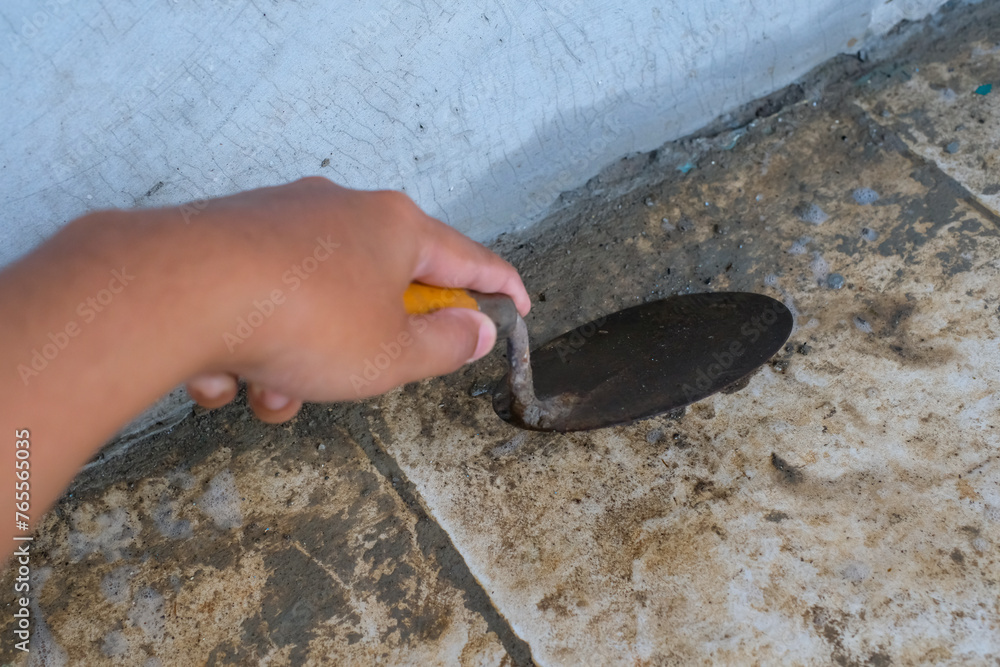 A hand scraping a cement stain on the floor. A worker is scraping the ...
