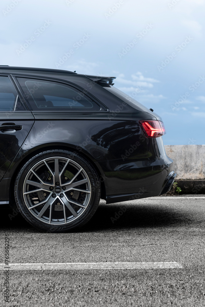 Black Audi RS6 Avant rear end side view, wheel focused, cloudy sky ...