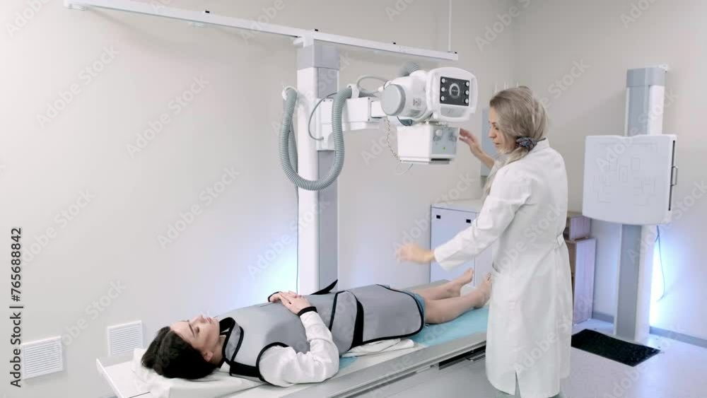 A female doctor installs an x-ray machine and prepares a young patient ...