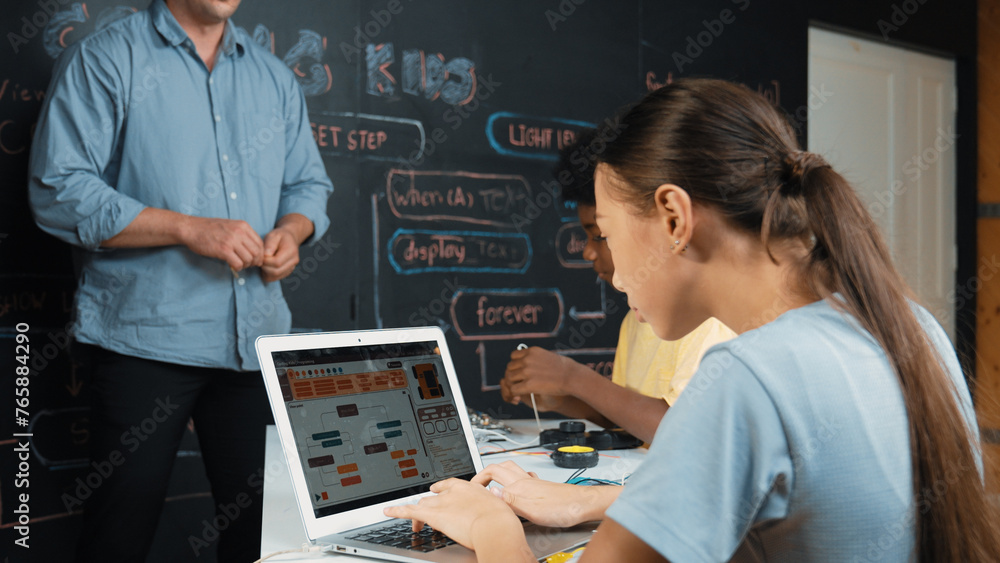 Teacher teaching about coding system while diverse academic student fixing main board at table ...
