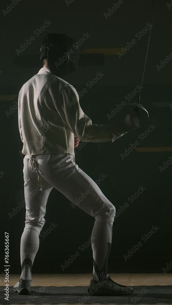 Vertical side full footage of male foil fencer coming to fencing piste ...