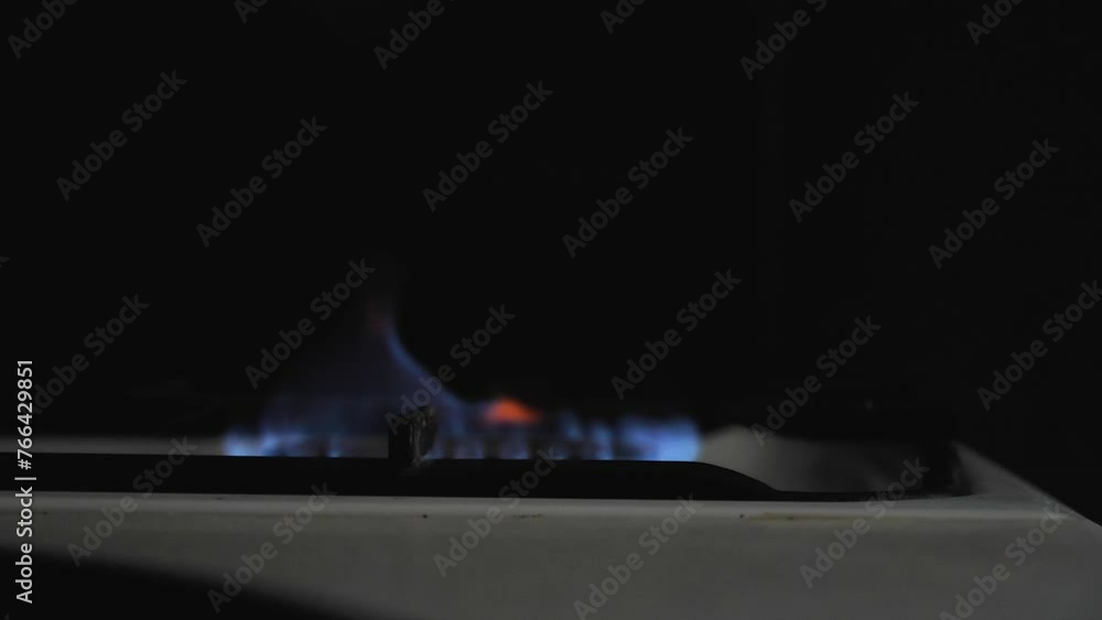 Close-up of a gas cooker burner with a blue flame. The tongues of fire ...