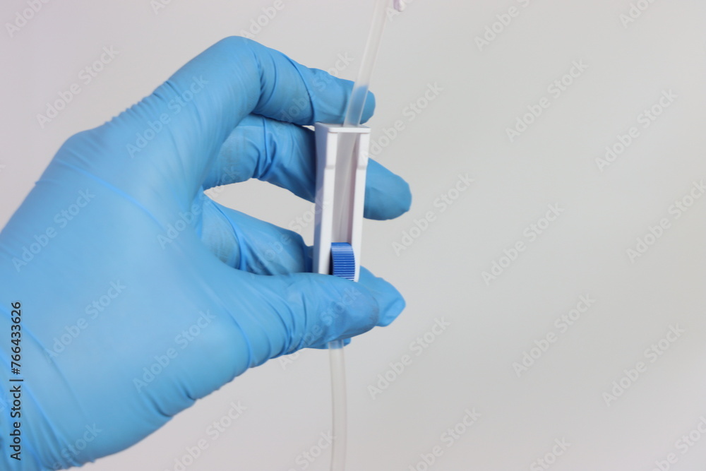 Healthcare professional wearing gloves adjusting the roller clamp of ...