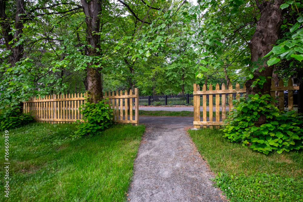 The opening of a wooden picket fence at the end of a concrete pathway ...
