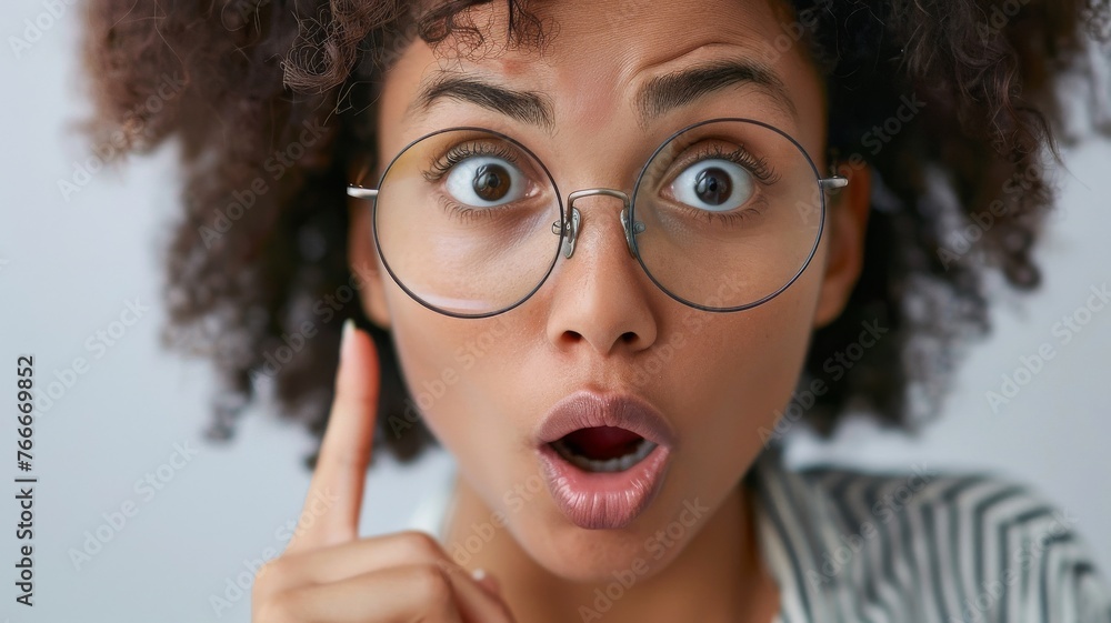 Astonished woman with glasses raising finger in eureka moment, suitable ...