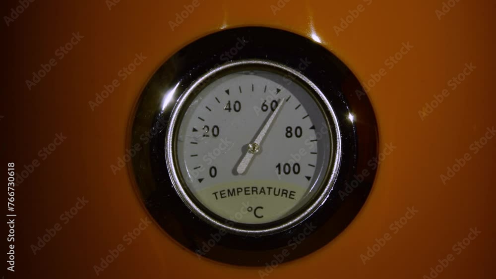 Moving instrument pointer on front side of orange vintage temperature ...
