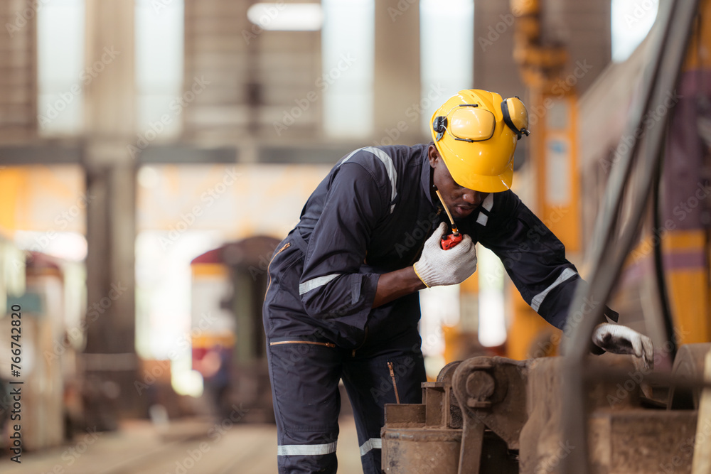 Railway technician in uniform and helmet inspect the train wheels ...