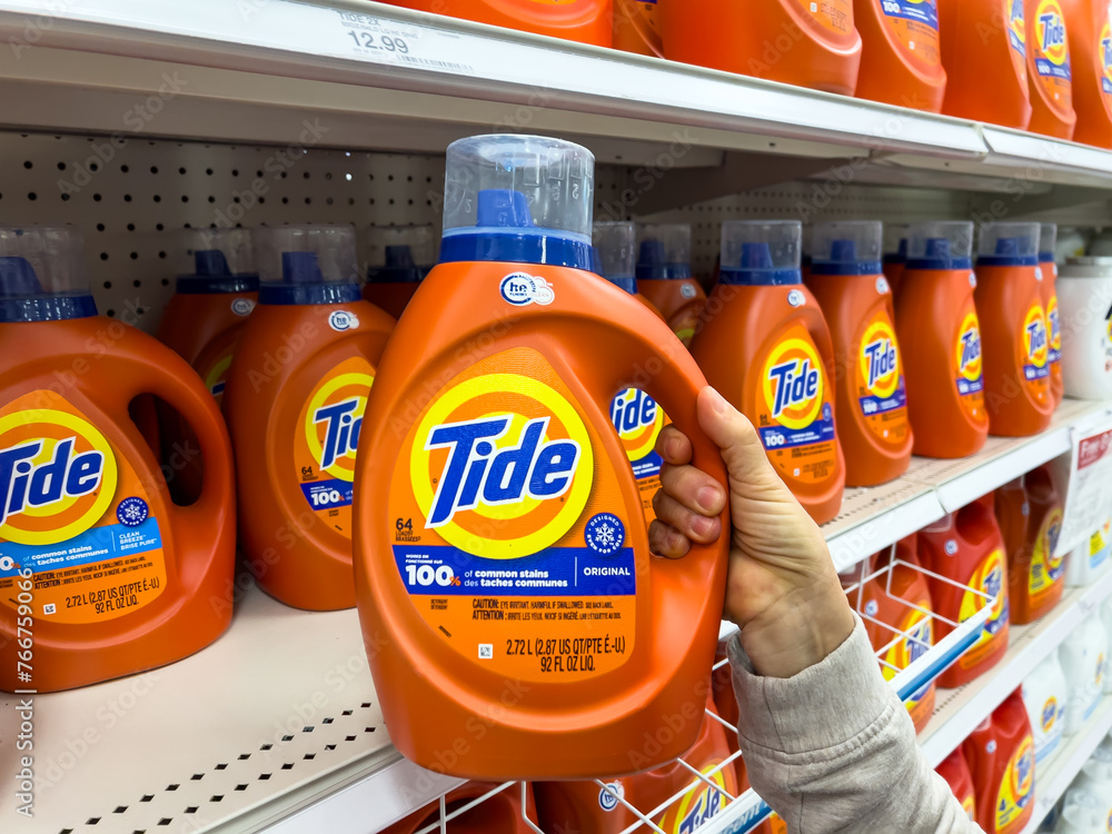 Shopper holding a plastic container of Tide brand liquid laundry ...
