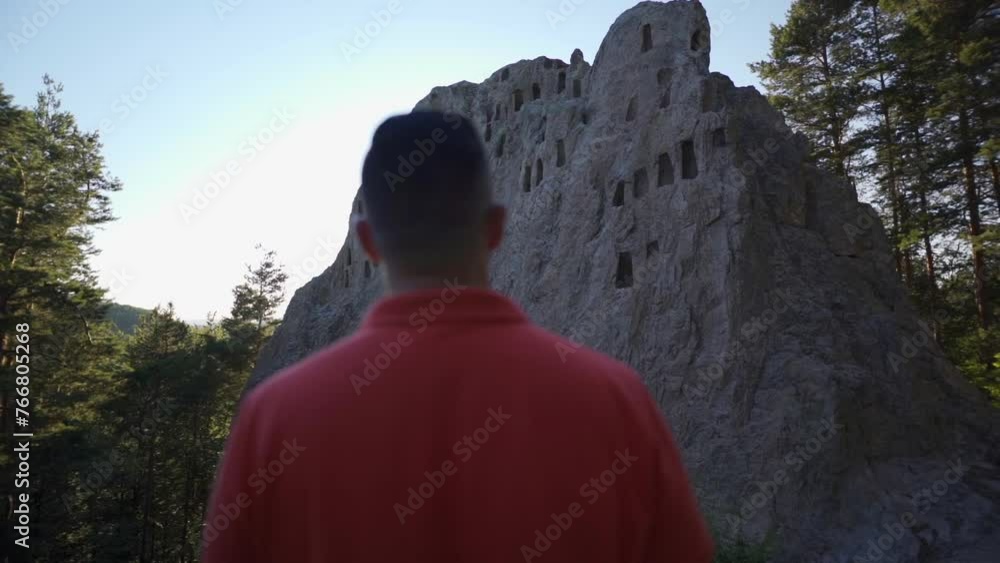 Standing in front of a natural rock formation of trapezoidal niches ...