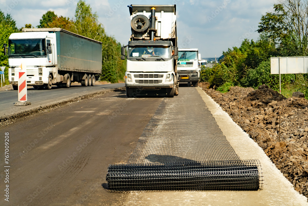 Worker is carrying roll of rebar for the installation of guard rail on ...