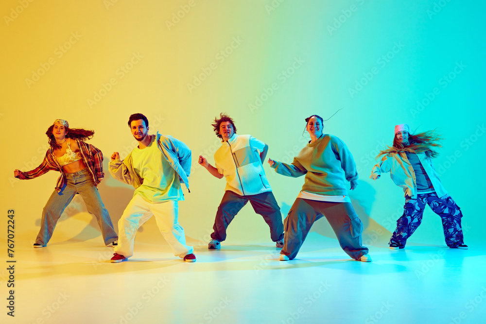 Synchronized movements. Group of young people dancing contemp against ...